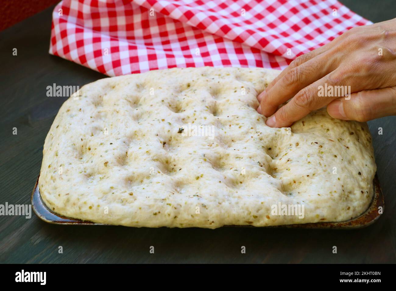 Creating dimples in the dough with fingertips for baking Italian ...