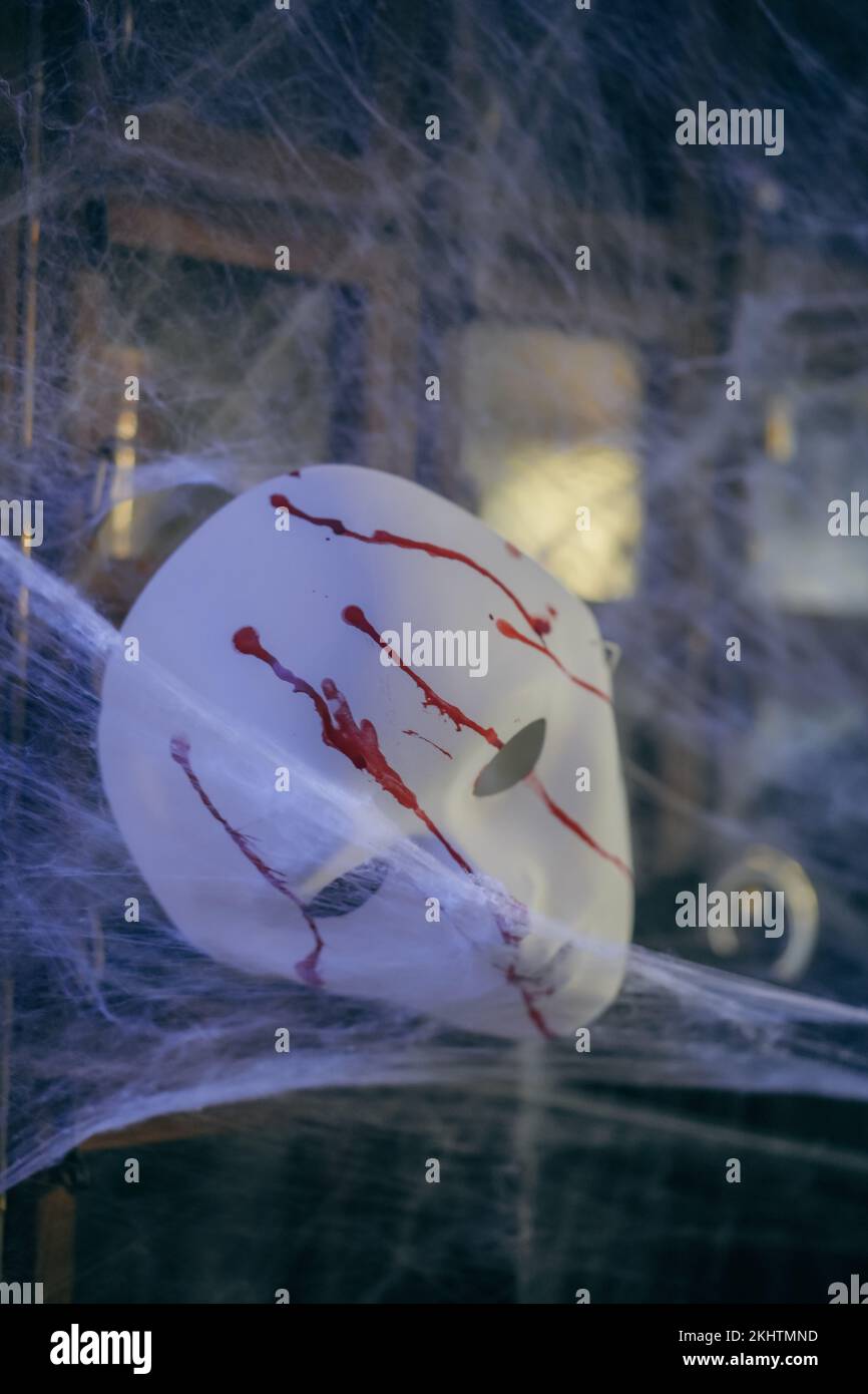 Color image of a white mask, painted with blood, in some spiderwebs and ...