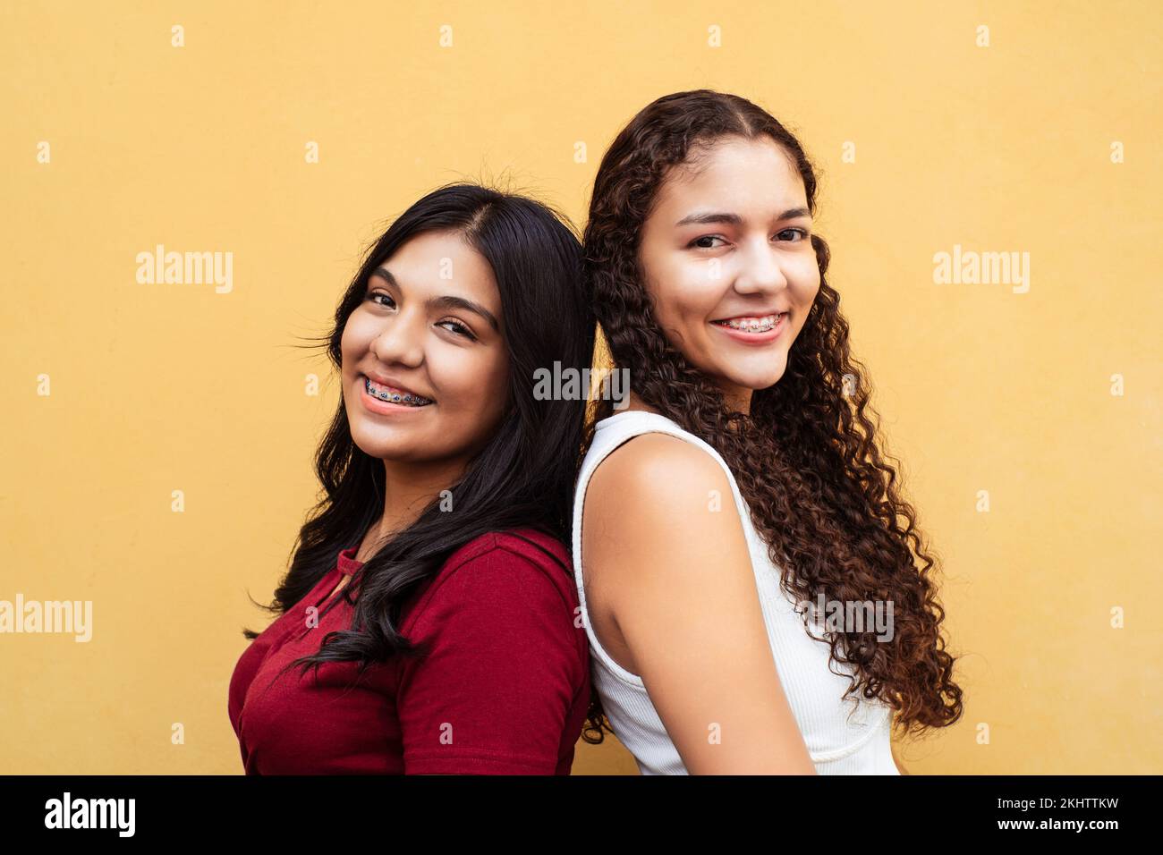 The two happy friends with brackets posing at camera over a yellow wall Stock Photo - Alamy