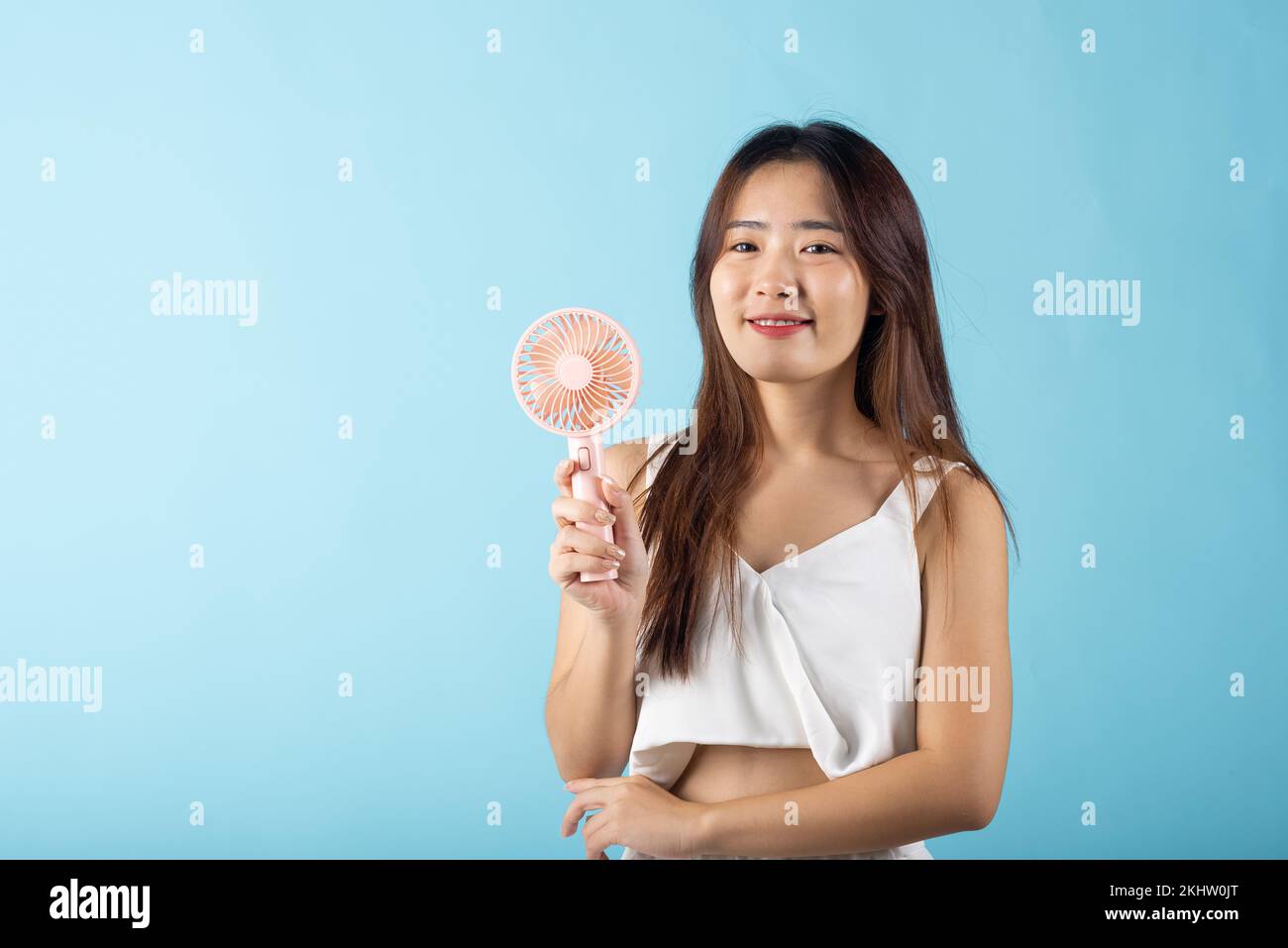 Asian beauty young woman holding pink portable electric mini fan near ...
