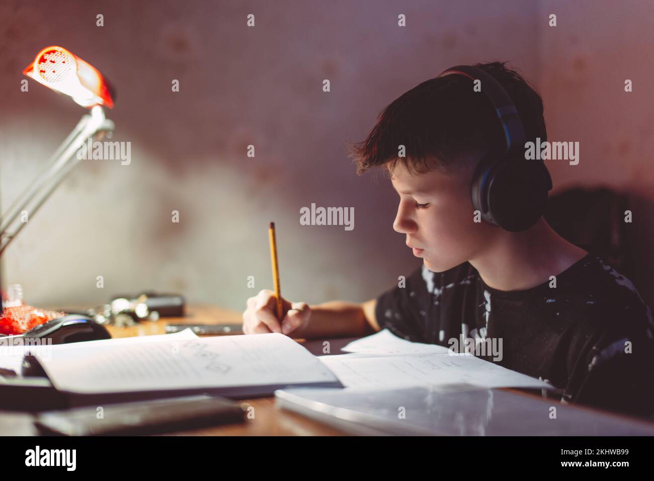 Little diligent boy doing his homework while listening music by ...