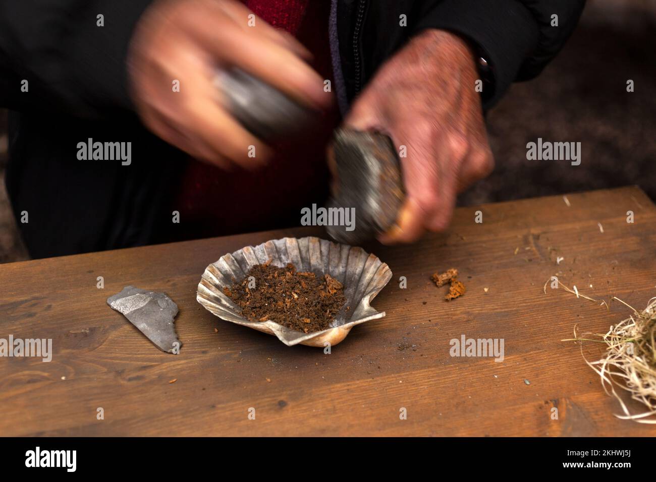 Close up of the hand of a man in action to start a fire using flint ...