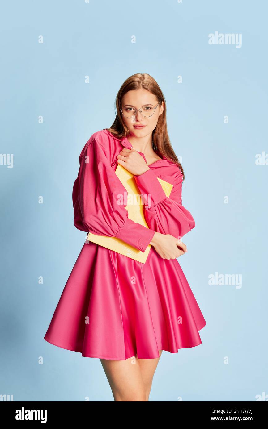 Portrait of young beautiful girl in stylish pink dress posing with ...