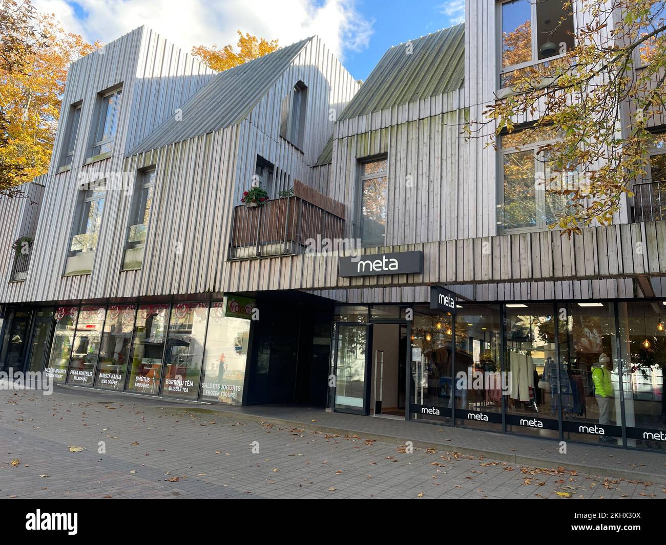 A modern facade of buildings and stores surrounded by yellow trees on ...
