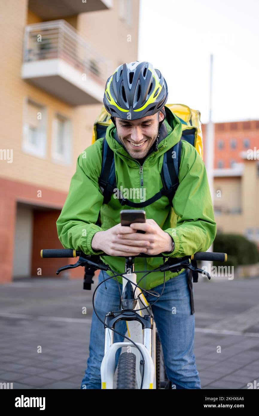 Smiling young man using bicylce to deliver boxes, documents and food at ...