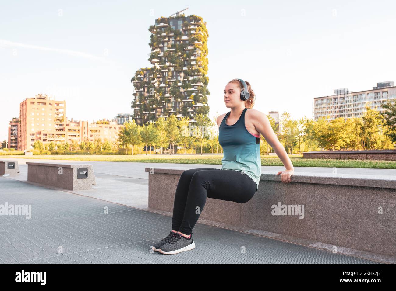 a young woman doing exercise outdoors in a public park, girl of the ...
