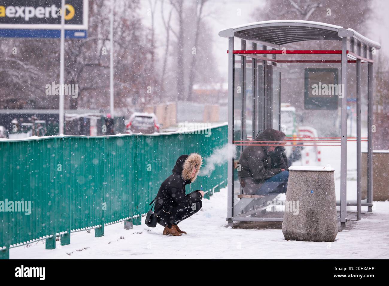 A woman is seen smoking, vaping near a bus stop during snowfall in ...