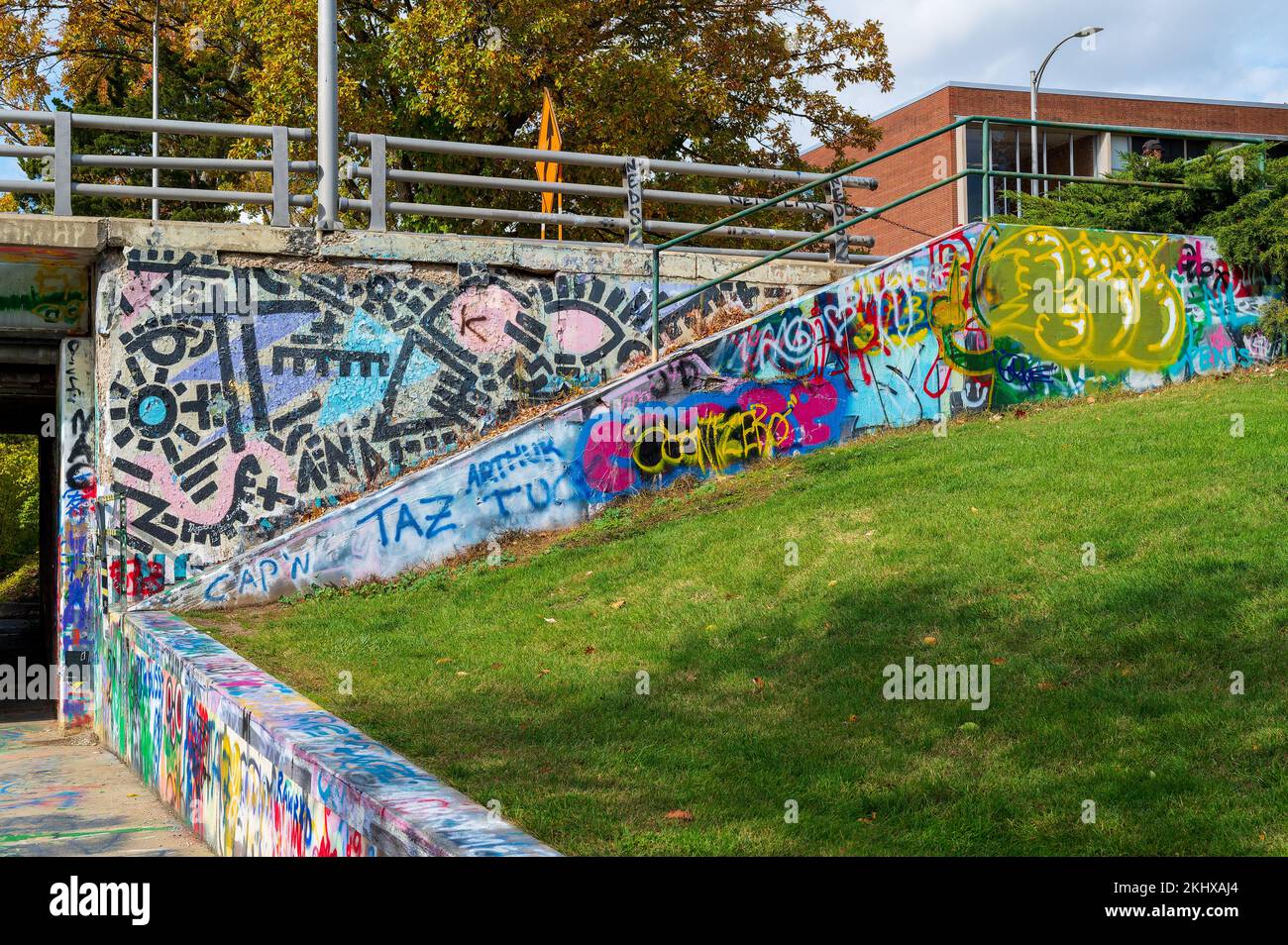 Colorful graffiti beneath a bridge next to a grassy hill Stock Photo ...