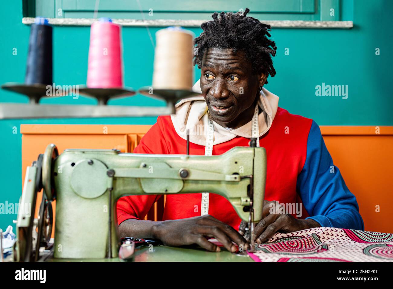 African adult tailor at work, artisan clothing manufacturer sewing with ...