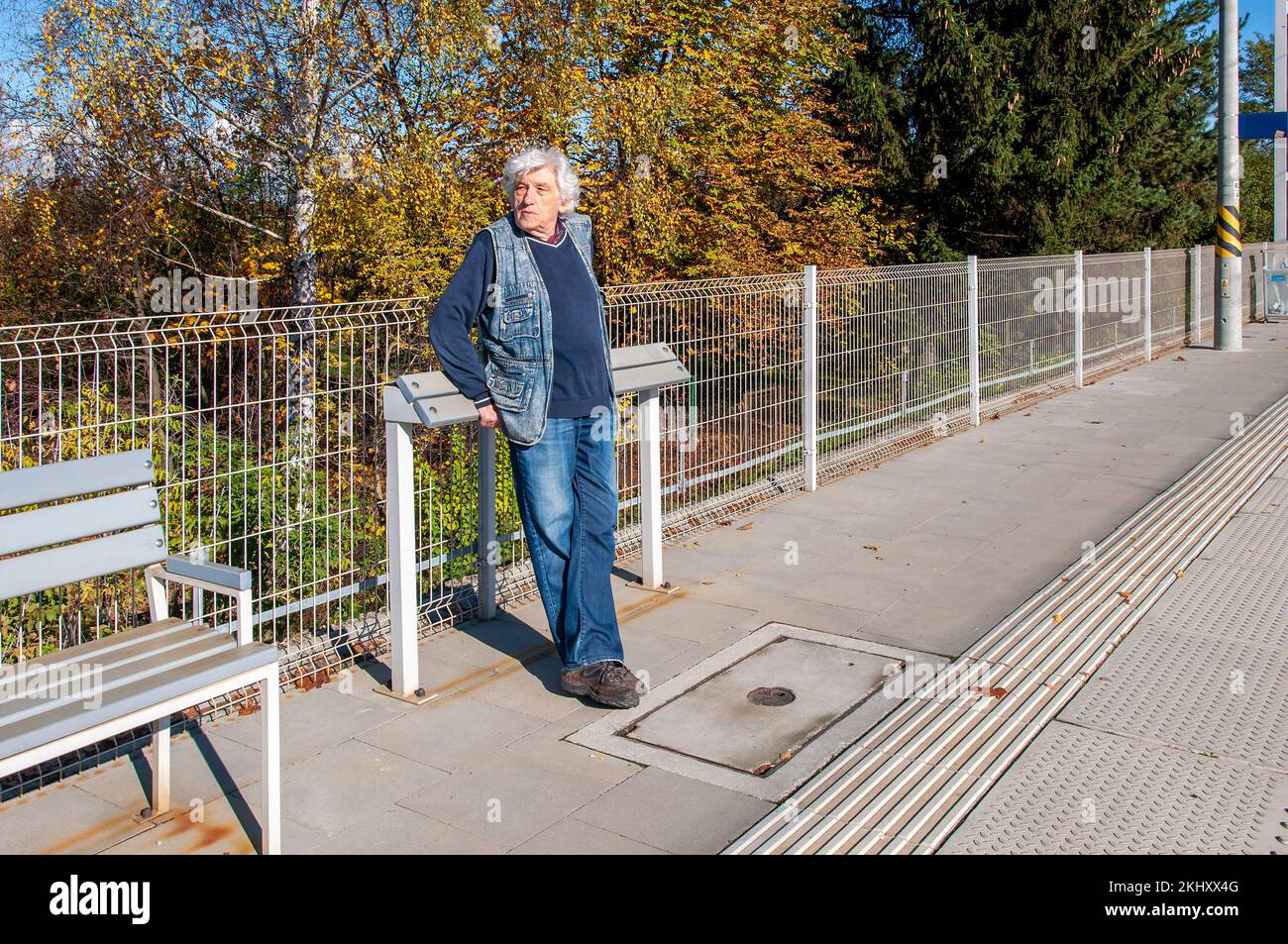 Senior leaning on a lean bench waiting for a train on a platform Stock ...