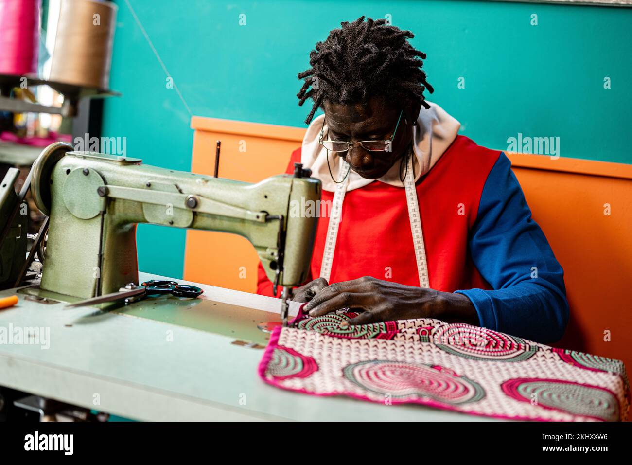 African adult tailor at work, artisan clothing manufacturer sewing with ...