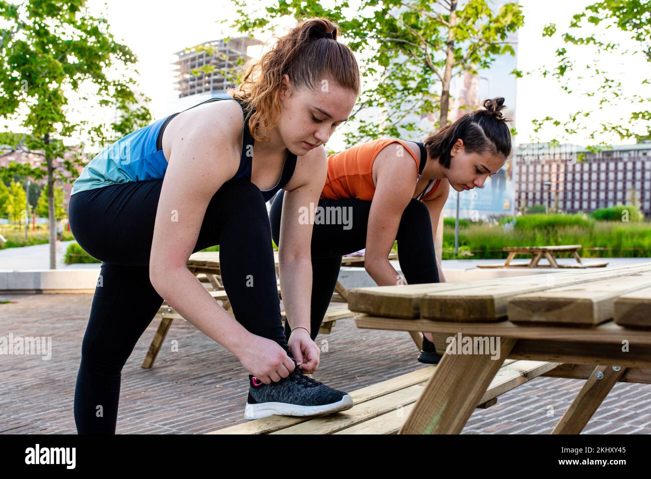 Two young women tie the laces of the shoes before running, jogging ...