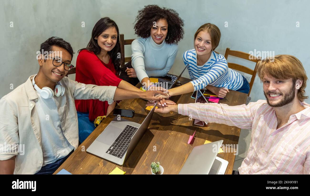 Group of happy colleagues of a small business stacking hands together ...
