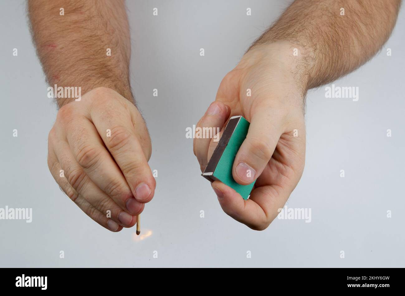 Lighting a match. Close-up of hands, matchbox and match on light-gray ...