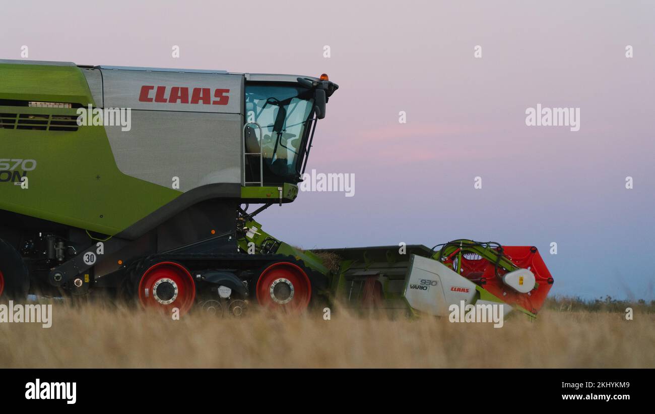 A CLAAS combine harvester on a hill at sunset Stock Photo - Alamy