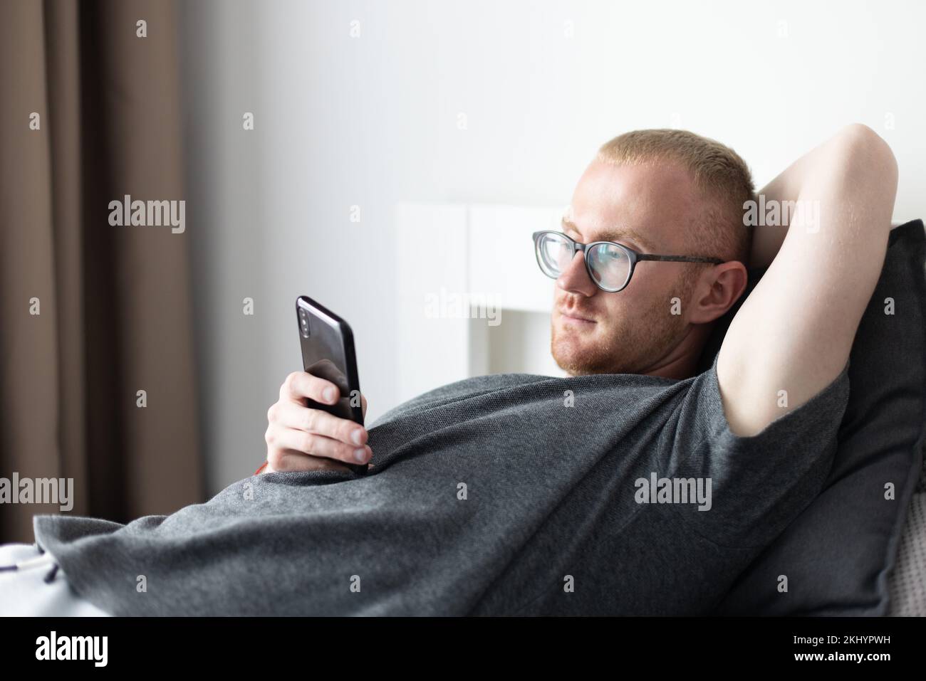 Man laying on a couch with mobile phone. Relaxing at home Stock Photo ...