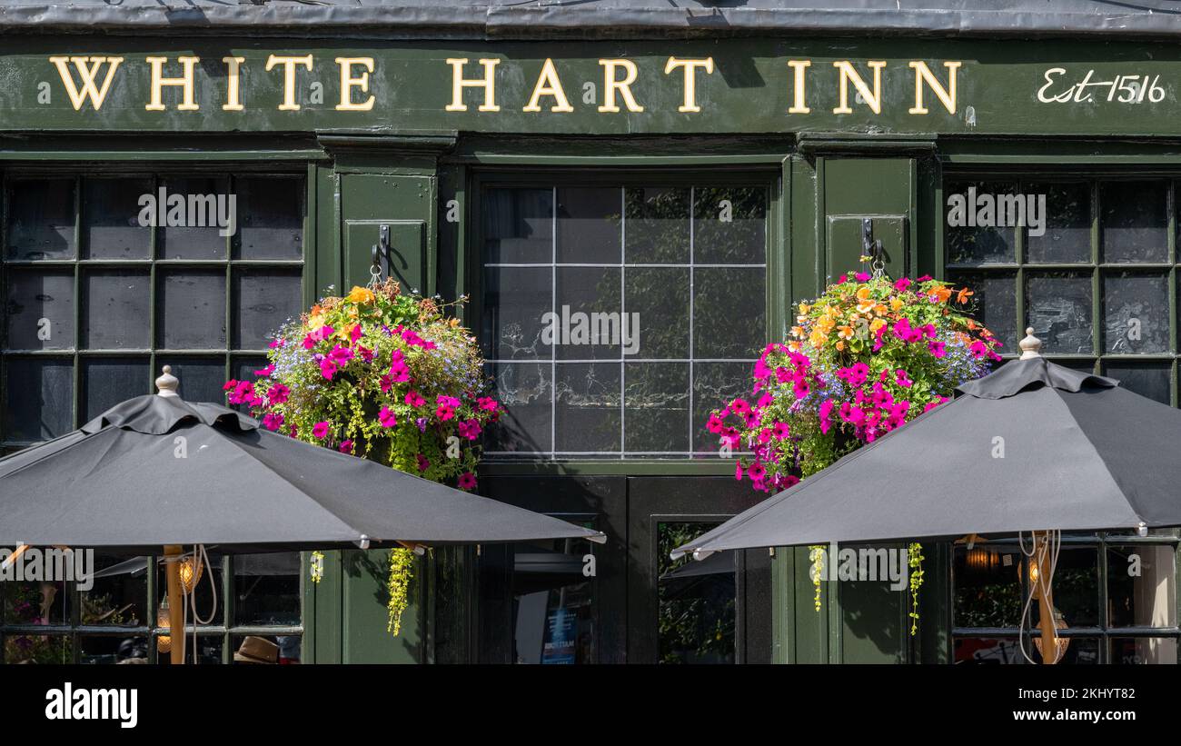 Colourful flower baskets hang outside the 16th century White Hart Inn ...