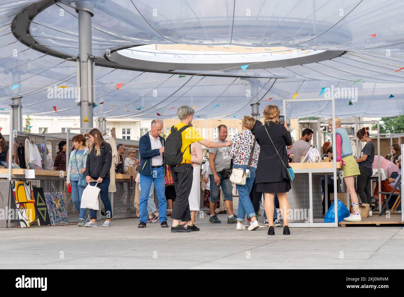 A group of people standing by stands of paintings during an art fair in ...