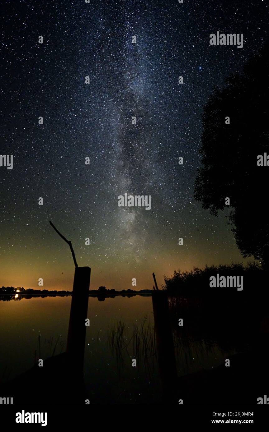 A vertical of a dark sky with a lot of shining stars above a mirror ...