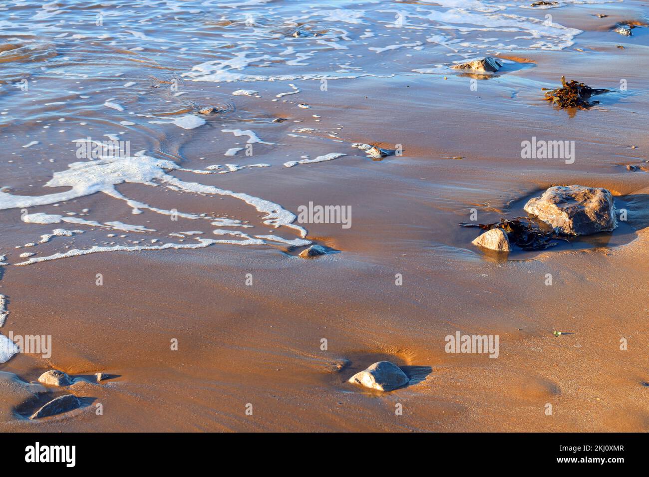 White surf from a gentle wave washing up a sandy beach Stock Photo - Alamy