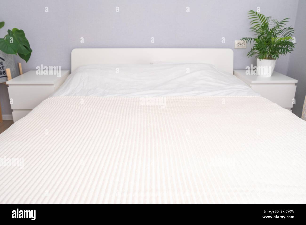 A beautiful modern white room with large spacious bed made with fresh ...