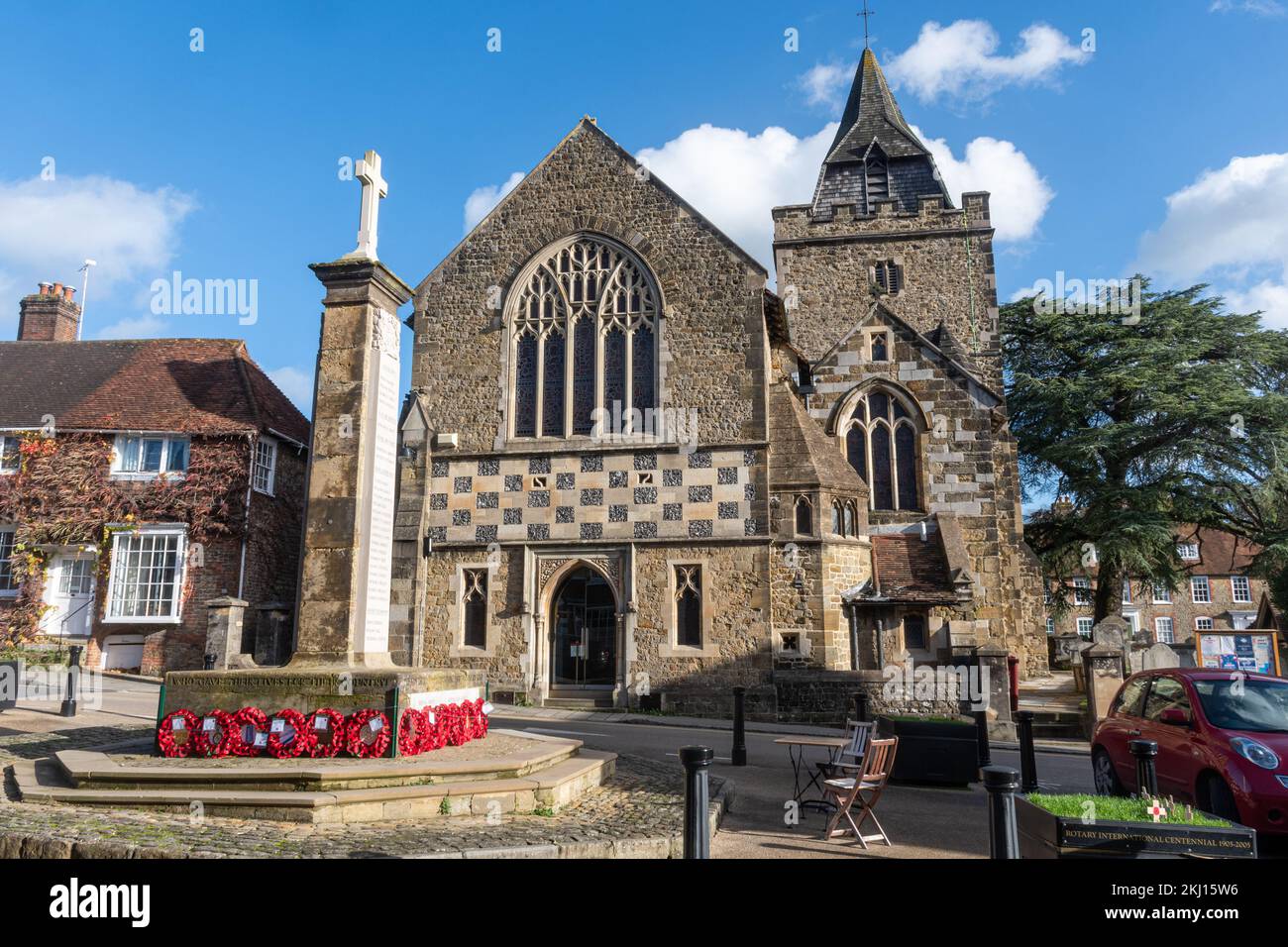 War memorial surrounded by poppy wreaths in front of the parish church ...