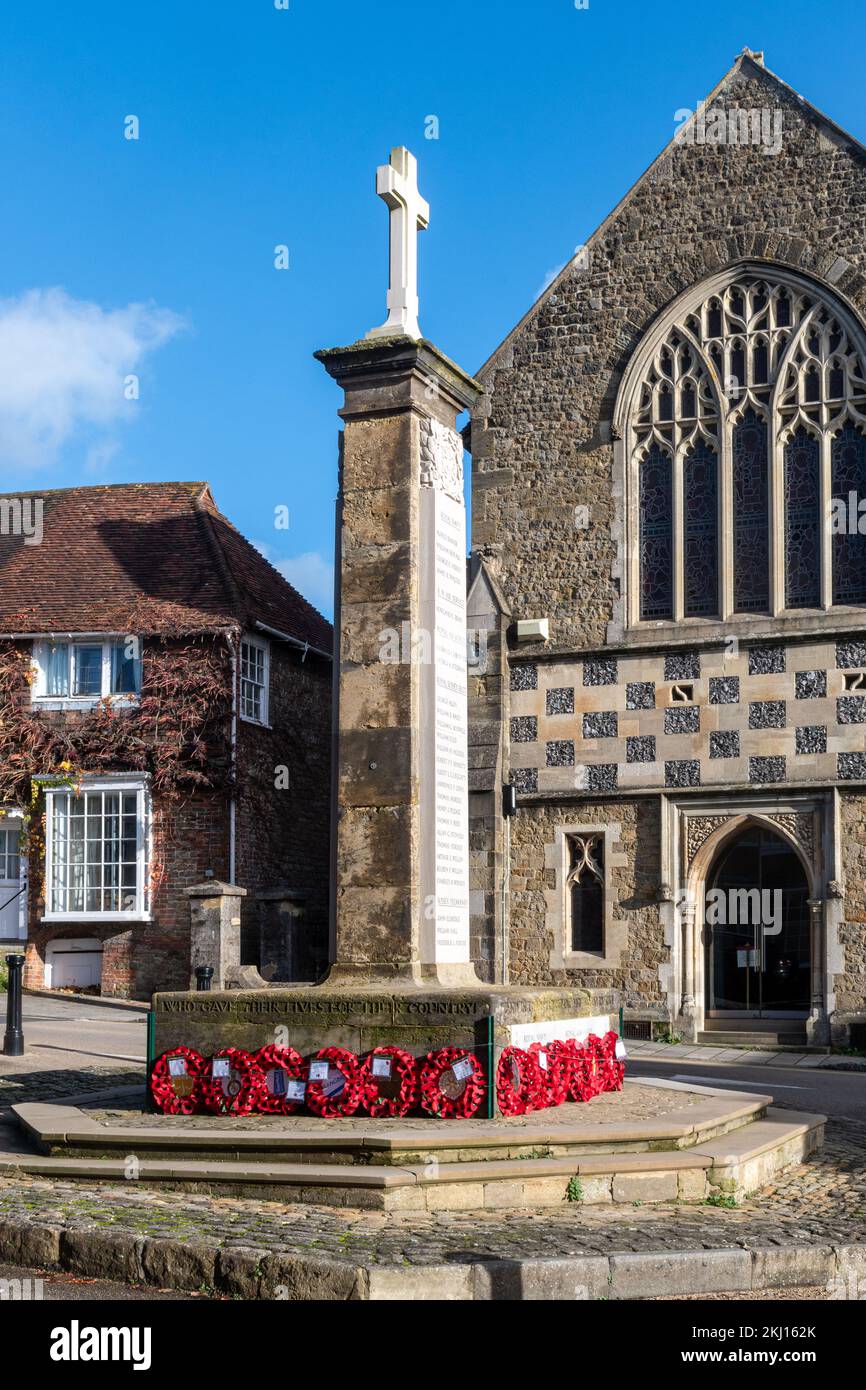 War memorial surrounded by poppy wreaths in front of the parish church ...