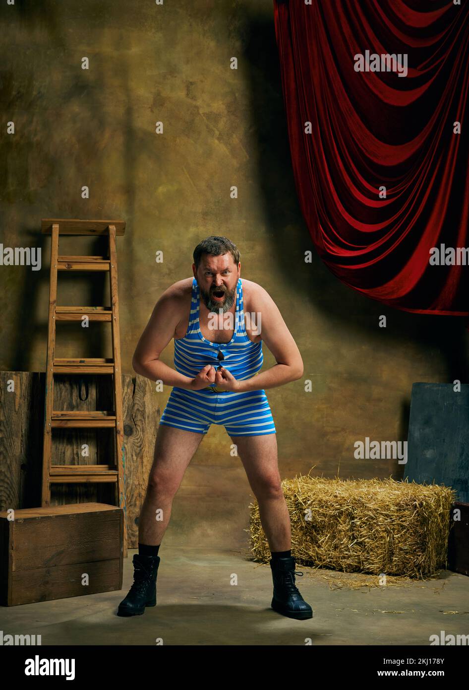 Winner emotions. Mature man, retro circus strongman wearing striped ...