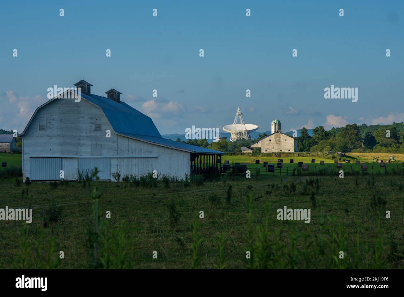 Large radio telescope in American landscape between barns in the ...