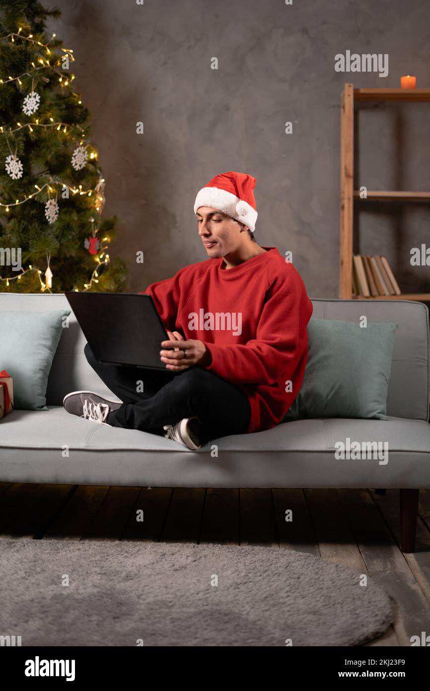 Smiling young male working with laptop on christmas eve, blogger in ...