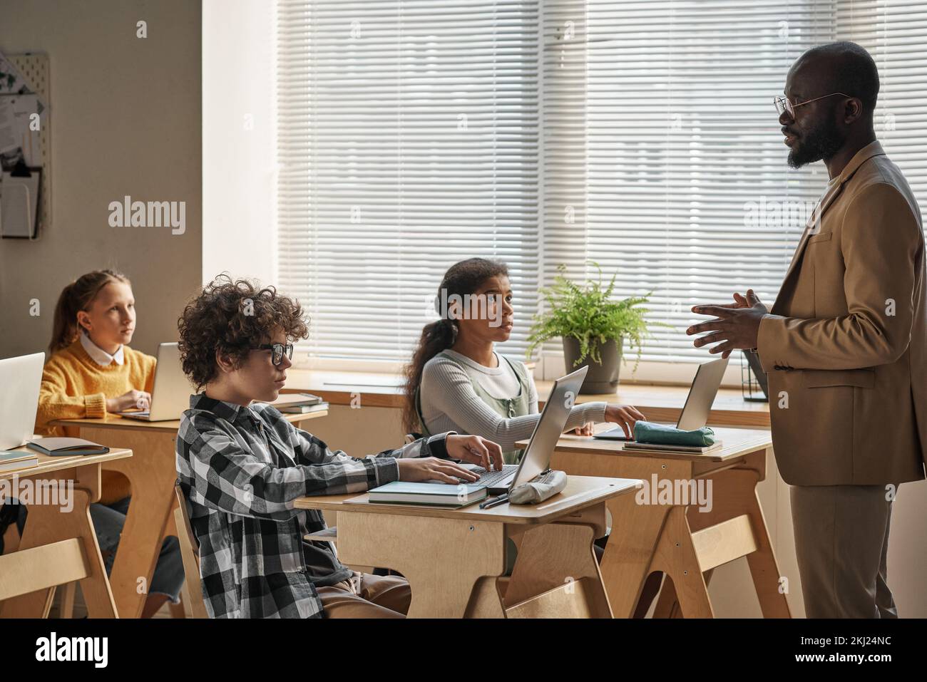 African American teacher explaining how to use computer to group of ...