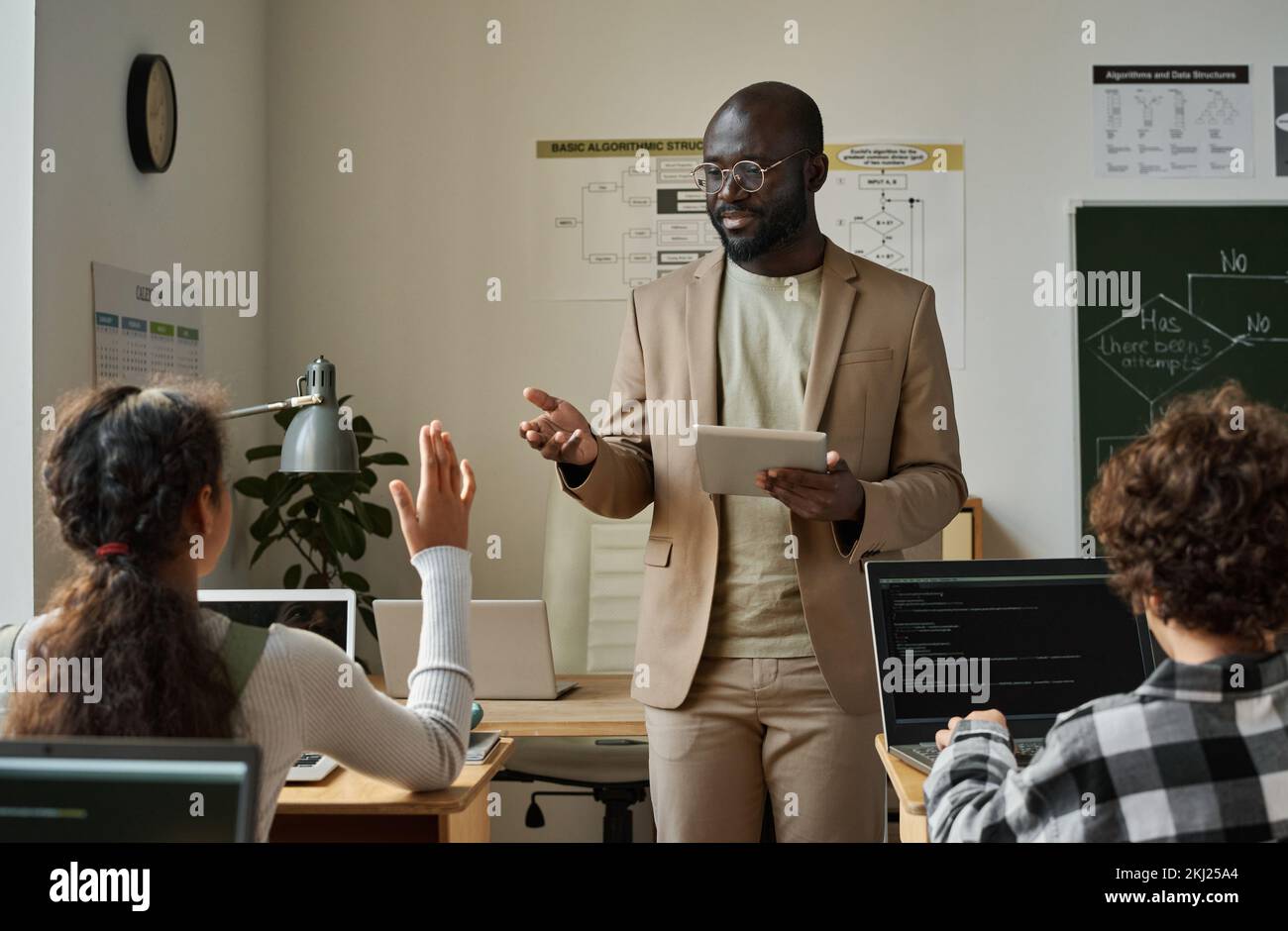 African American teacher using digital tablet while working with ...