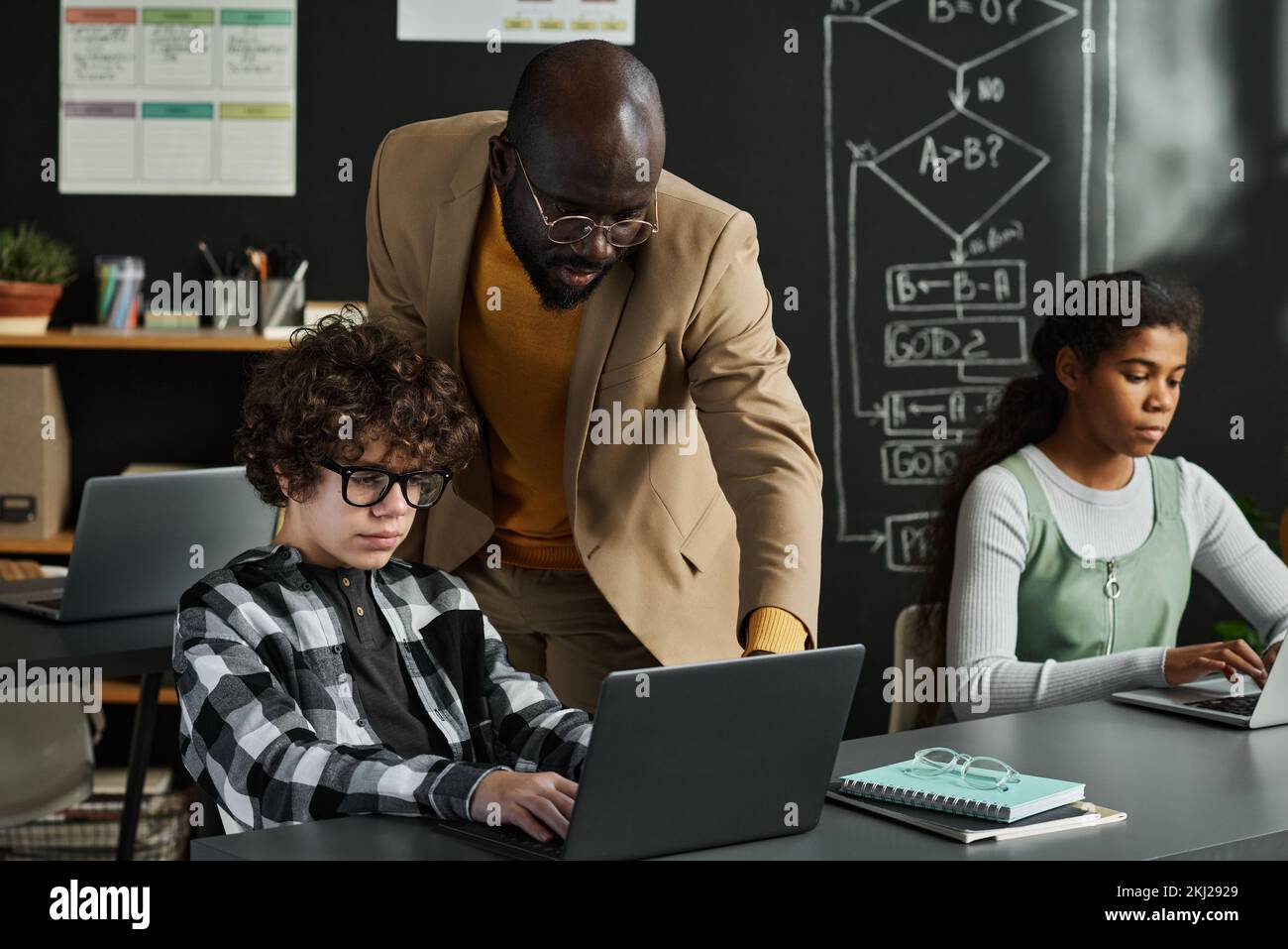 African American teacher teaching children to work with computer at ...