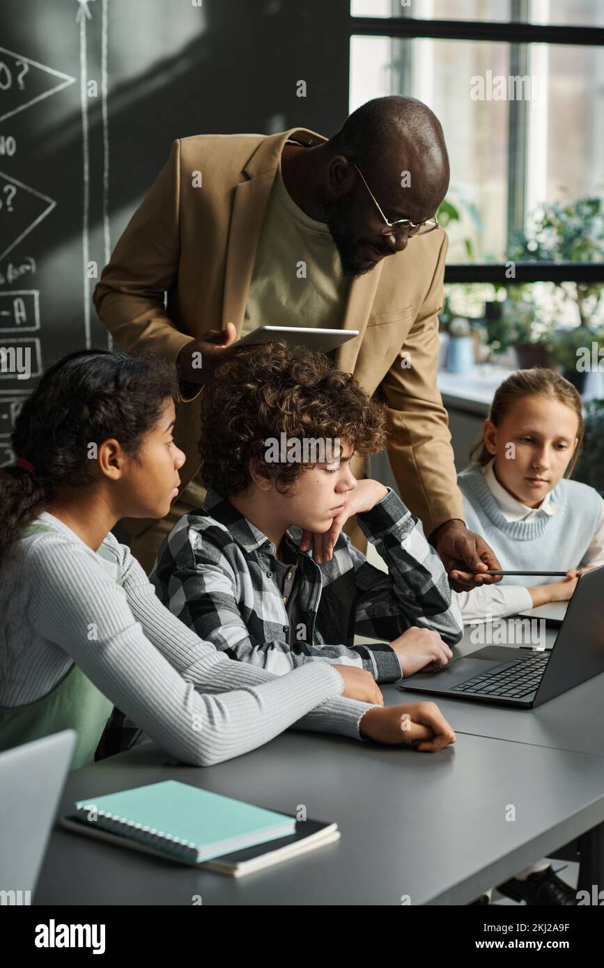 African American teacher showing the work of computer program on laptop ...