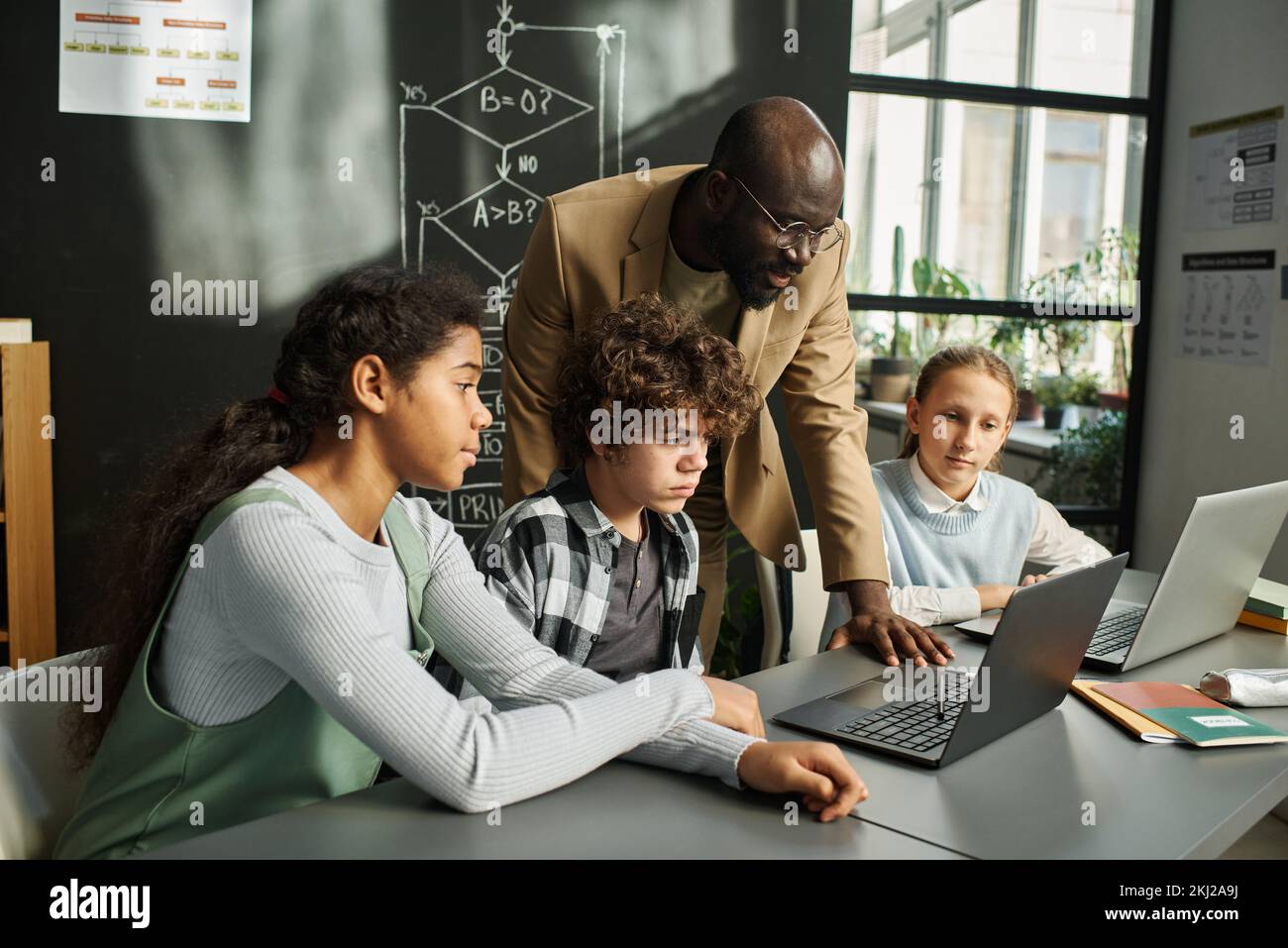African American teacher discussing computer program with children at ...