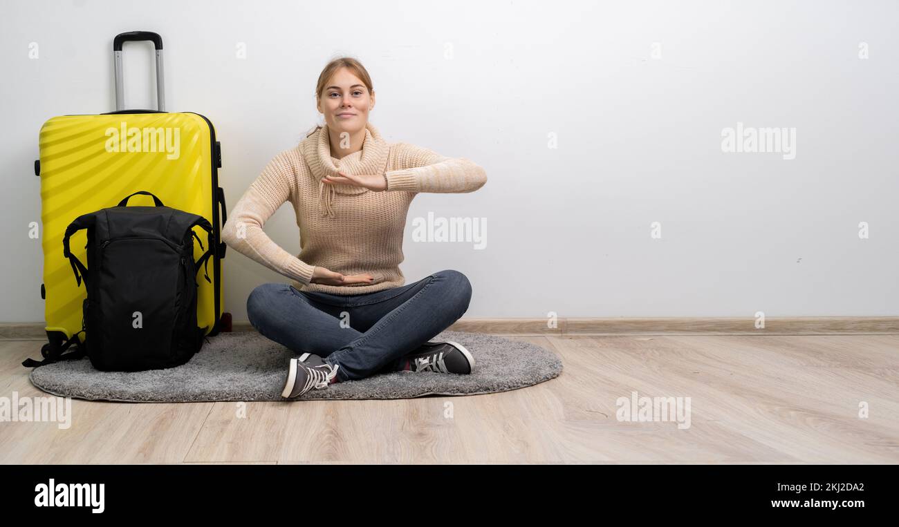 Woman traveler with suitcase in sweater holding something with both ...