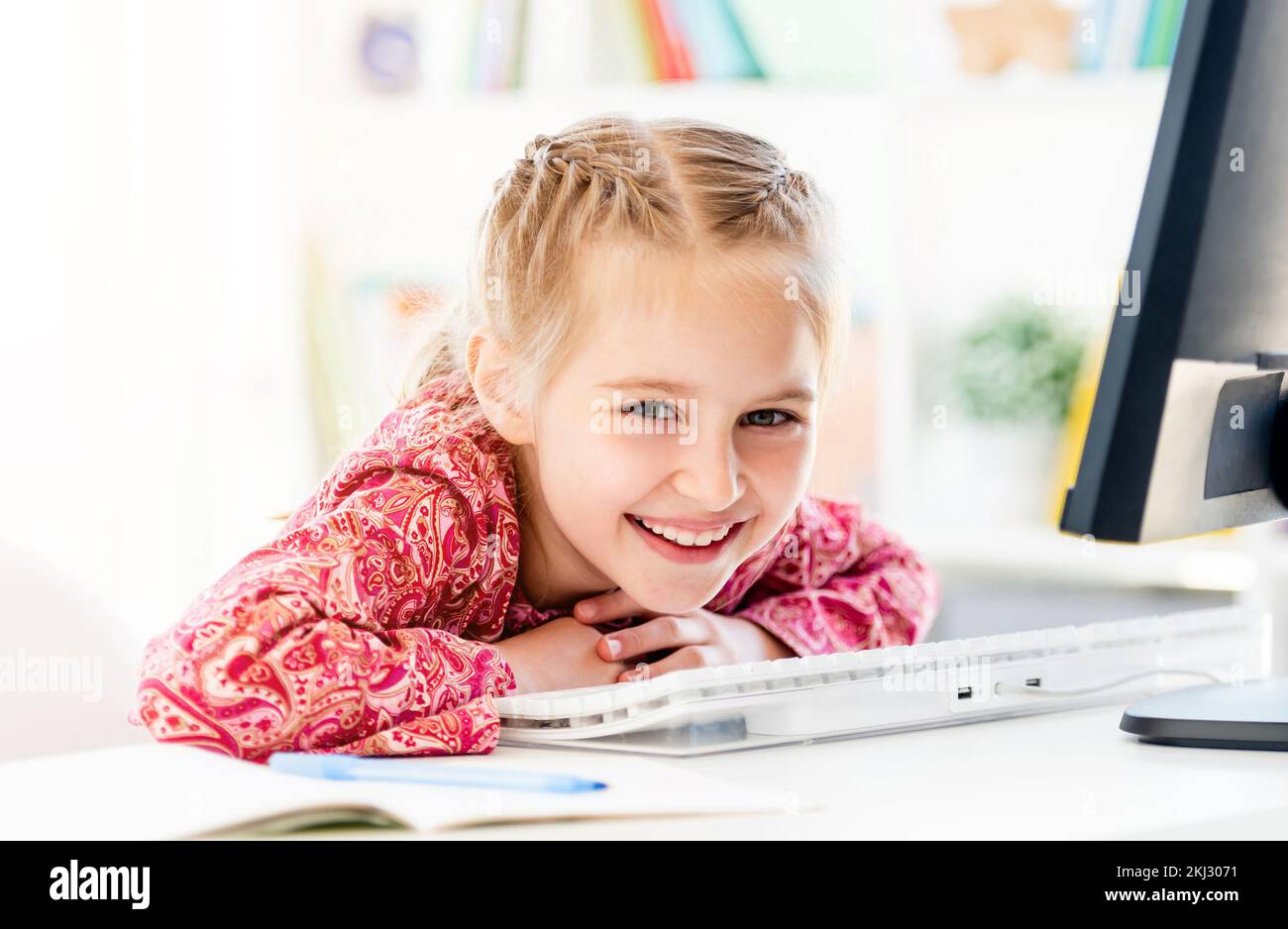 Smiling little girl at computer desk Stock Photo - Alamy