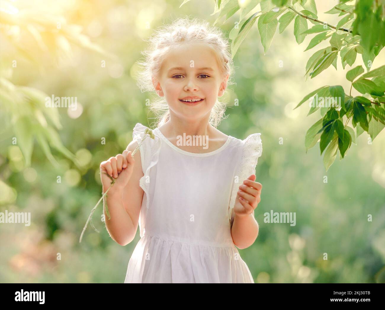 Cute little girl in beatiful white drass is having joy gathering ...