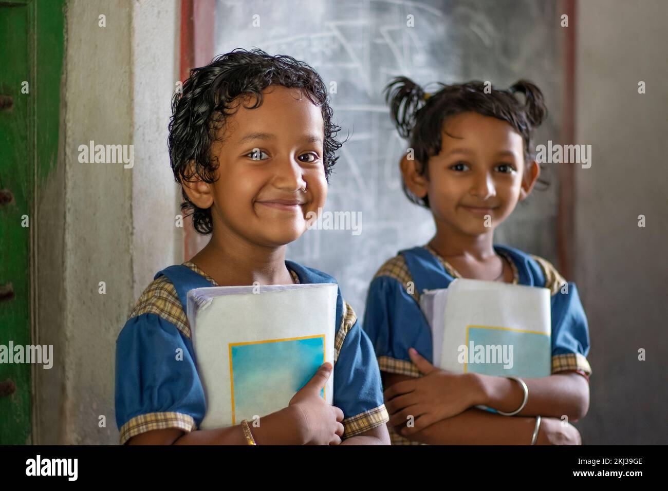 Three School Children's holding books standing at school Stock Photo ...