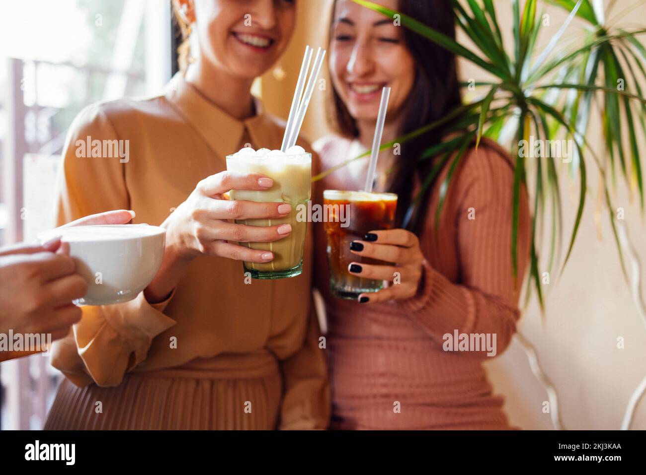 Happy young female friends having coffee break while relaxing at indoor ...