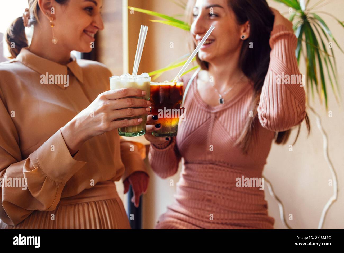 Happy young female friends having coffee break while relaxing at indoor ...