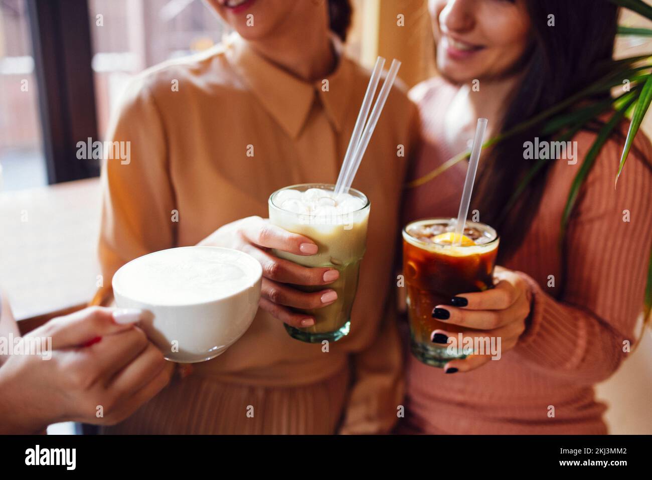 Happy young female friends having coffee break while relaxing at indoor ...
