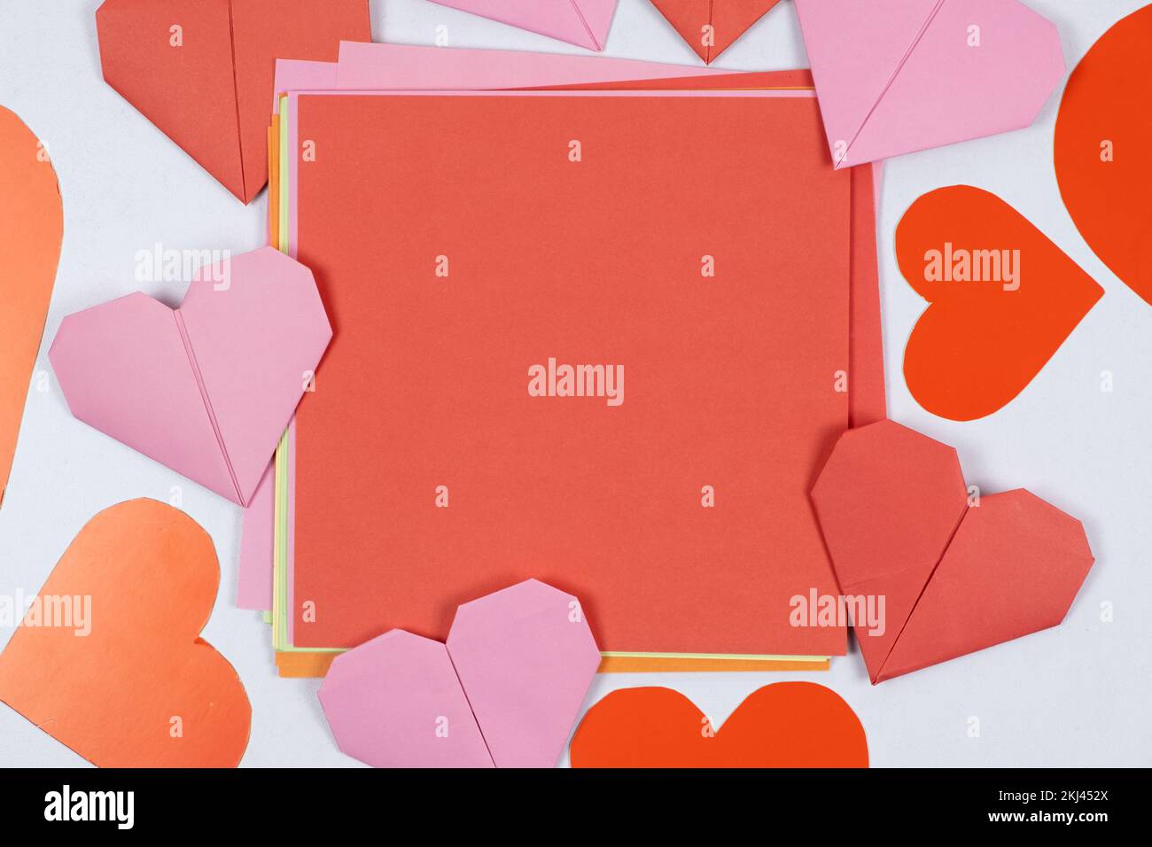 Origami pink and red hearts with sheet of paper place for text centered ...