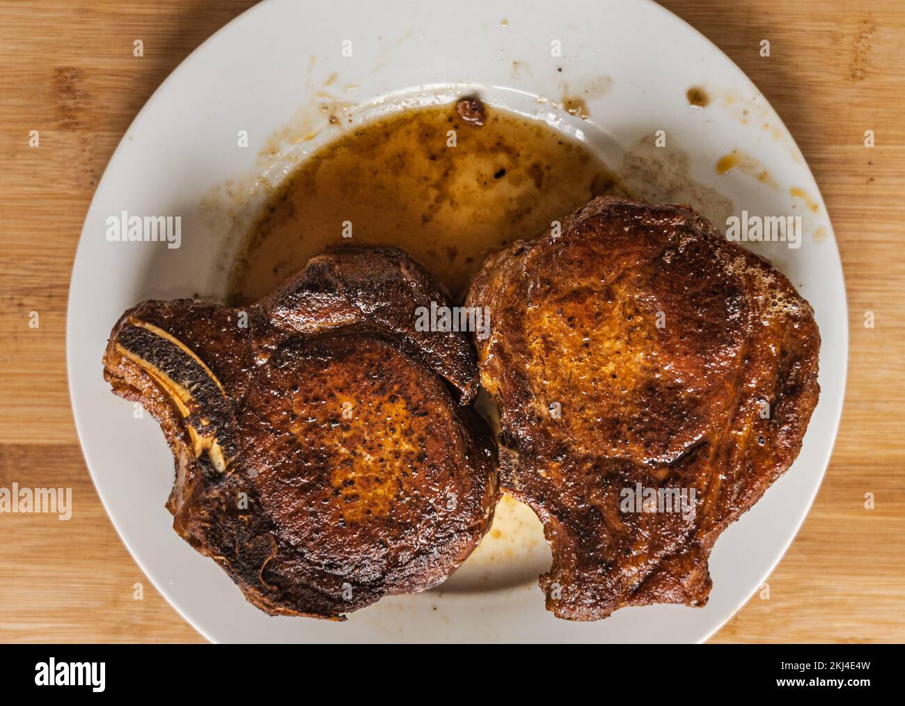 Grilled or pan fried pork chops on the bone in white plate. Overhead ...