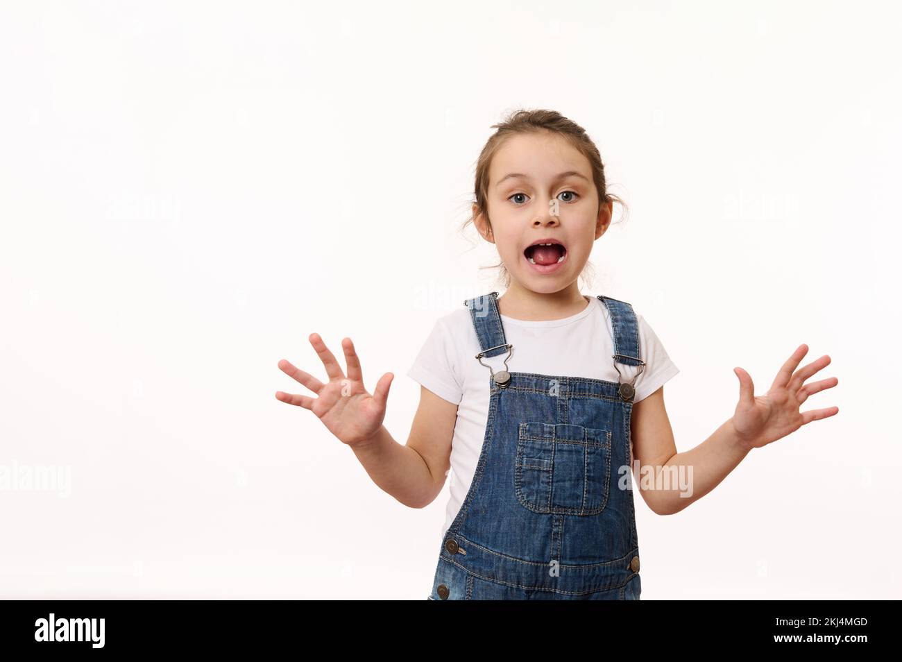 Emotional portrait of overjoyed baby girl, wearing blue denim overalls ...