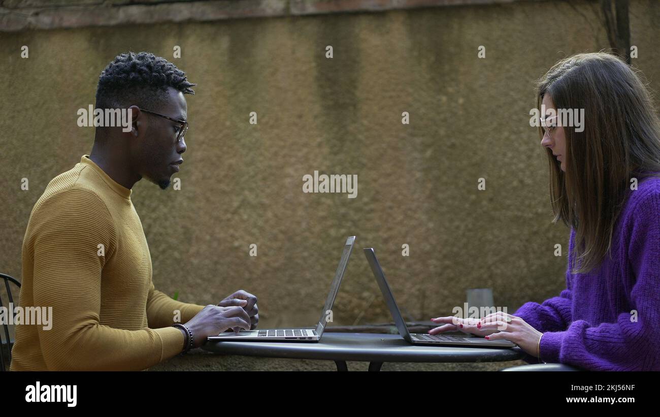 Candid interracial friends working outside with laptop computers Stock ...