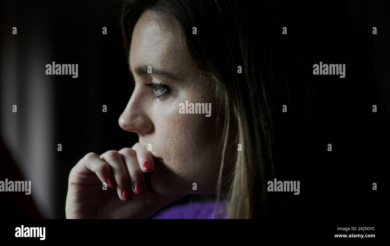 Anxious young woman standing by window concerned with life problems2 ...