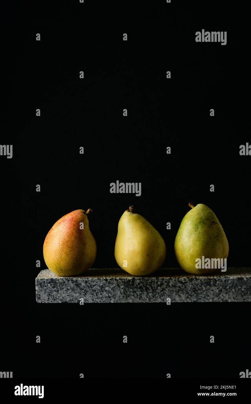 Three ripe yellow pears on a dark background Stock Photo - Alamy