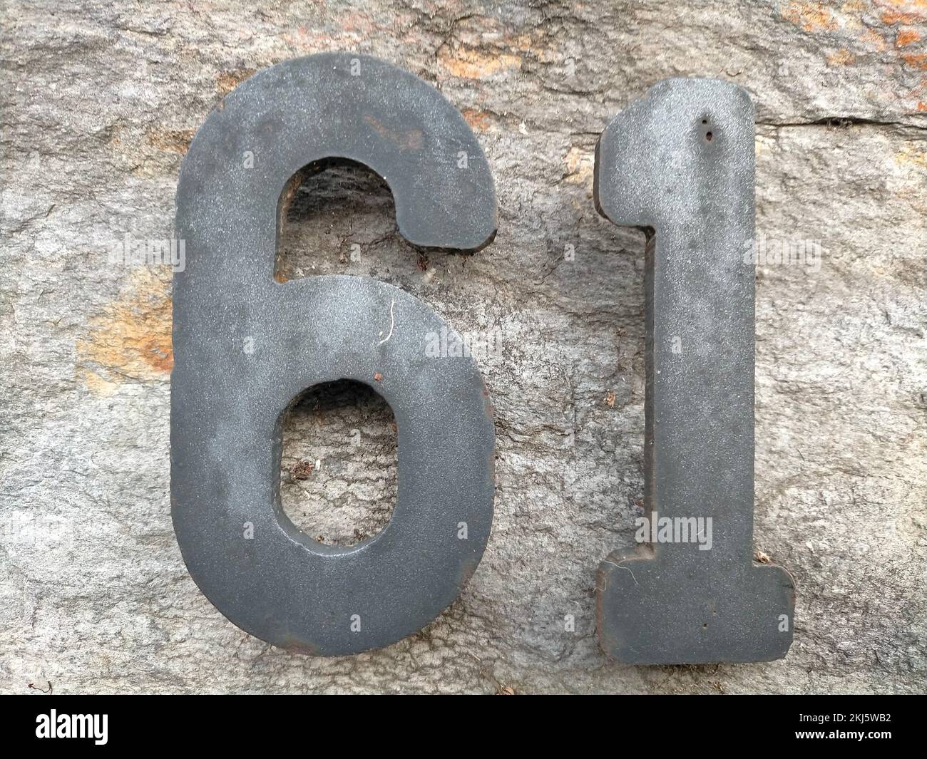A dark gray metal 61 door number on concrete wall Stock Photo - Alamy