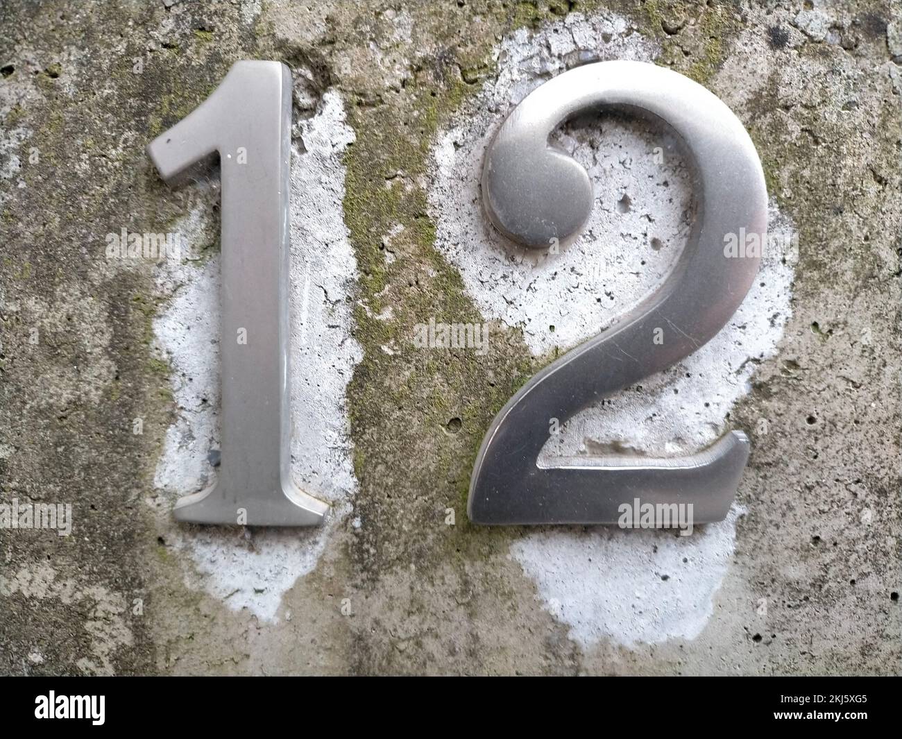 A dirty silver 12 door number on concrete wall Stock Photo - Alamy
